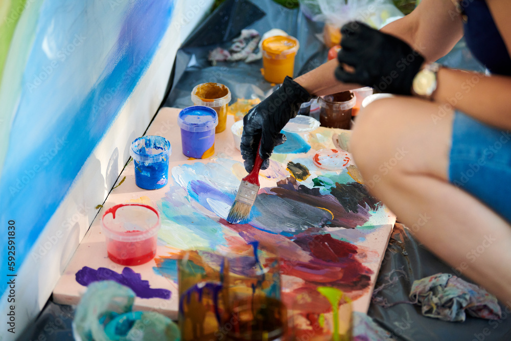 Artist hand in black gloves holds paint brush and choose color from ...