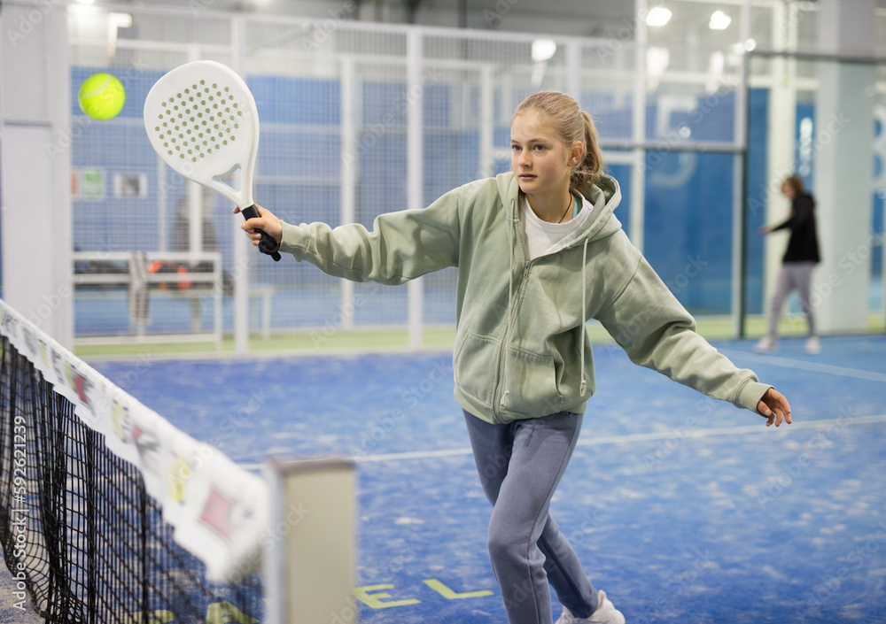 Teenage girl holding padel racquet in hand and ready to return ball ...