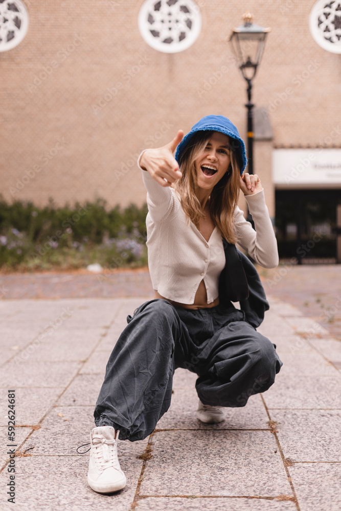 Full length radiant young caucasian girl kneels down against street ...