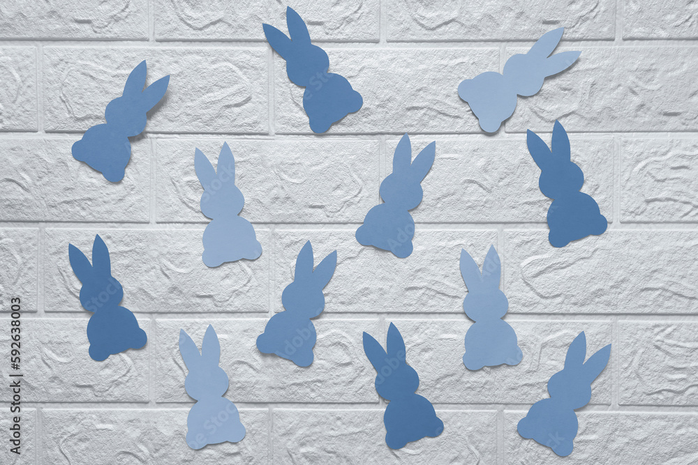 Home decor with paper rabbits. Blue paper bunnies against white brick ...