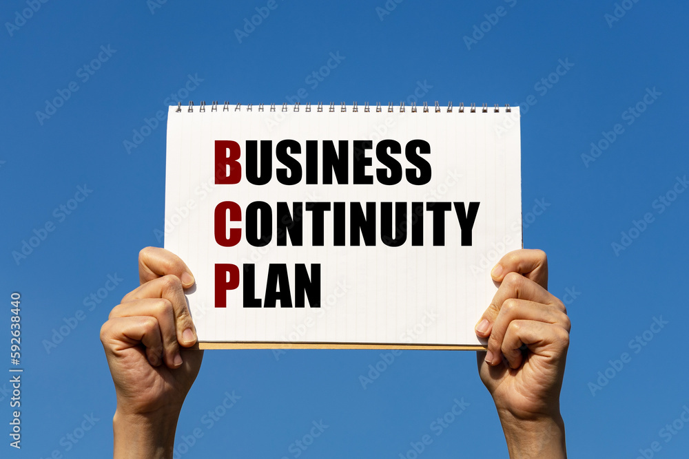 Business continuity plan text on notebook paper held by 2 hands with ...