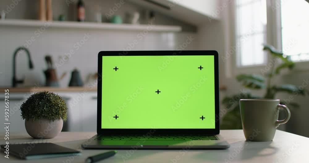 Laptop on table with green screen, close-up. Table in kitchen with ...