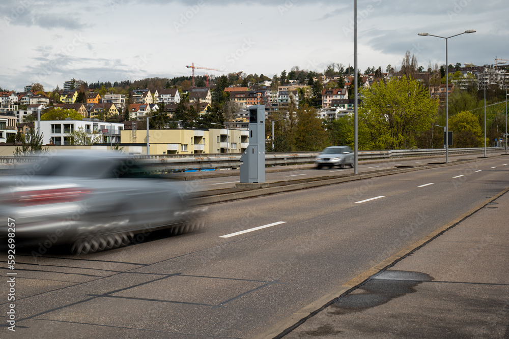 Road traffic speed trap camera in a gray box between 4 lanes of road in ...