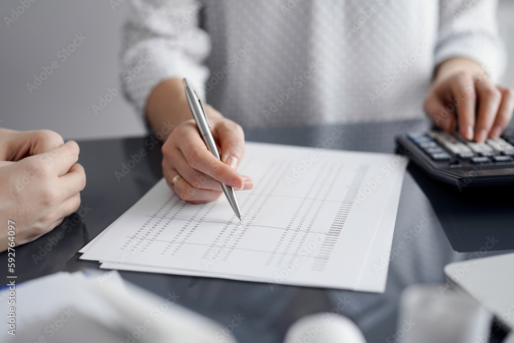 Woman accountant using a calculator and laptop computer while counting ...