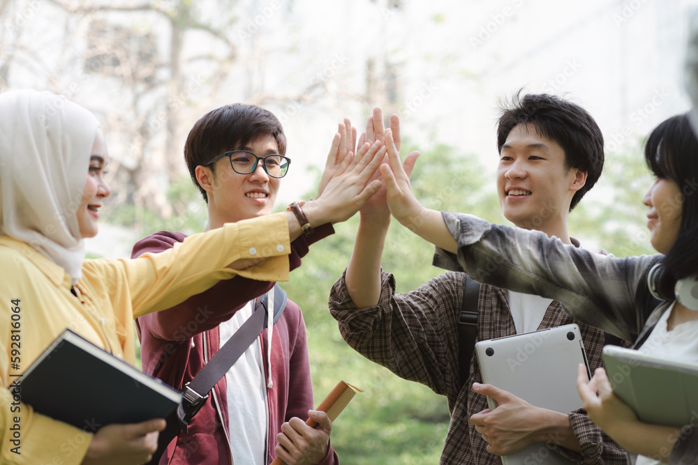 A group of diverse, multiracial young people are shown happily stacking ...