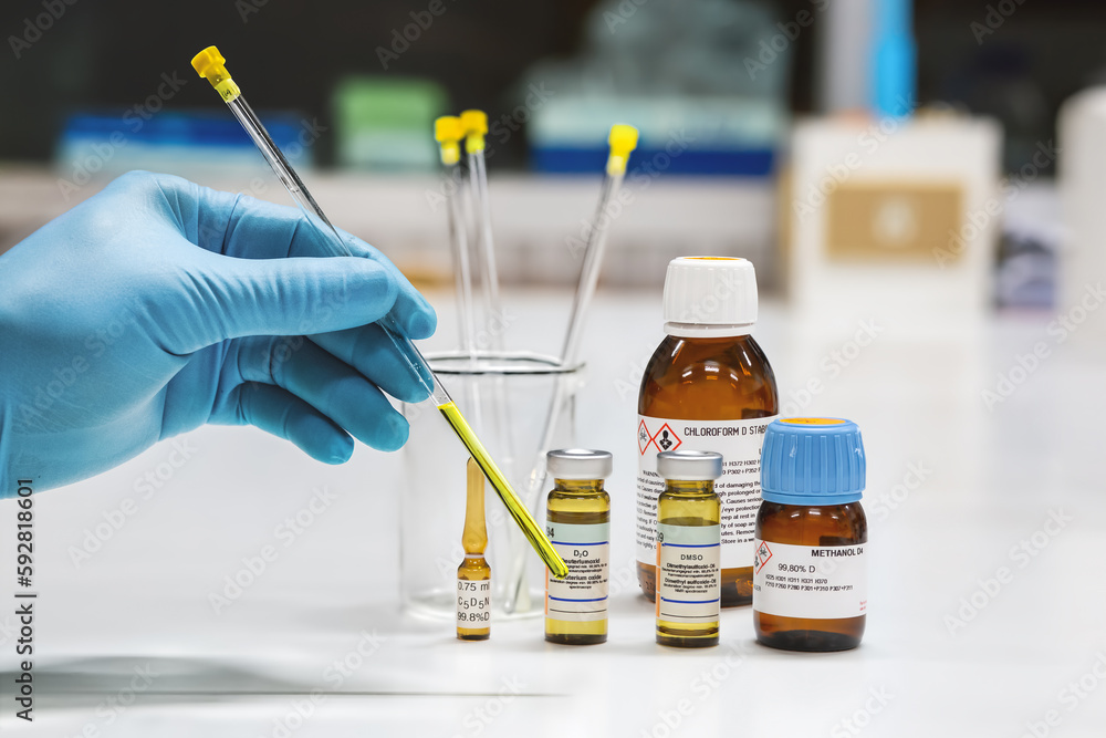 Hand of scientist shows yellow sample solution was prepared in NMR ...