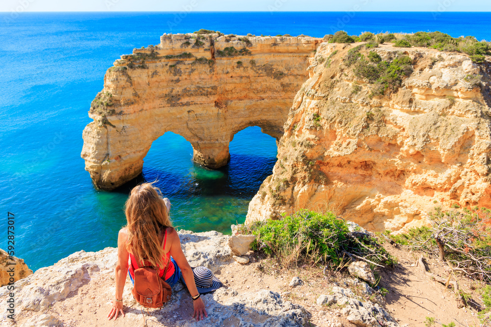 Woman tourist looking at heart shape rock formation, coast of the ...