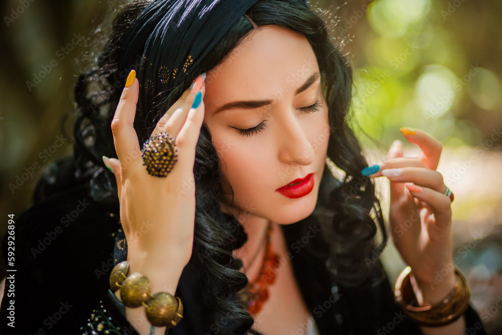 A gypsy woman in the forest with a wooden smoking pipe in her hands ...