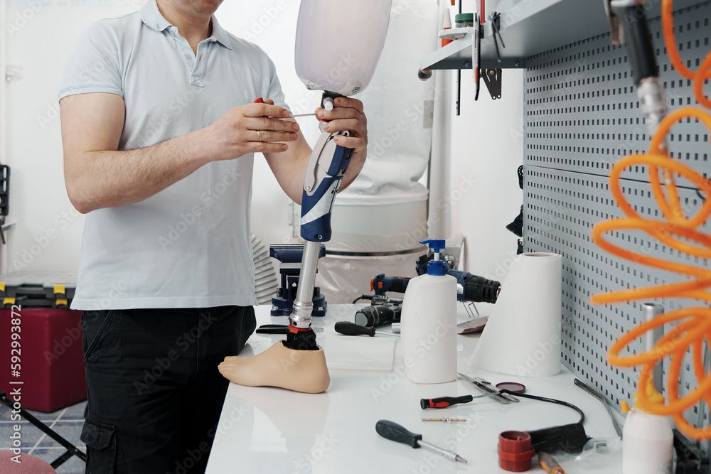 Crop unrecognizable craftsman adjusting and bending modern prosthetic ...
