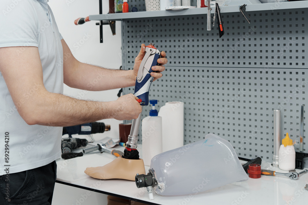 Crop unrecognizable craftsman adjusting and bending modern prosthetic ...