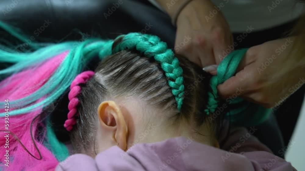 The process of braiding fashionable braids from bright pink and blue ...