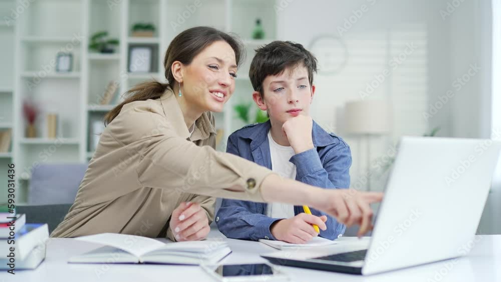 Mother and son watch an online lesson on a laptop computer. school ...