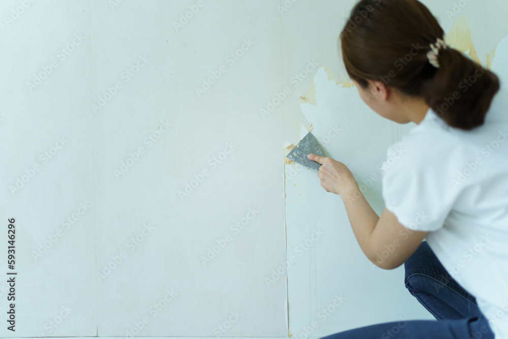 Asian woman fixing and removing a broken wallpaper by herself. Close up ...