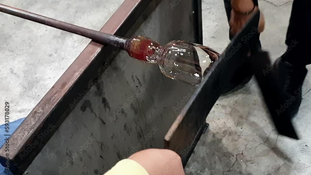Glass blowing process use wood paddle to create smooth bottom of glass ...