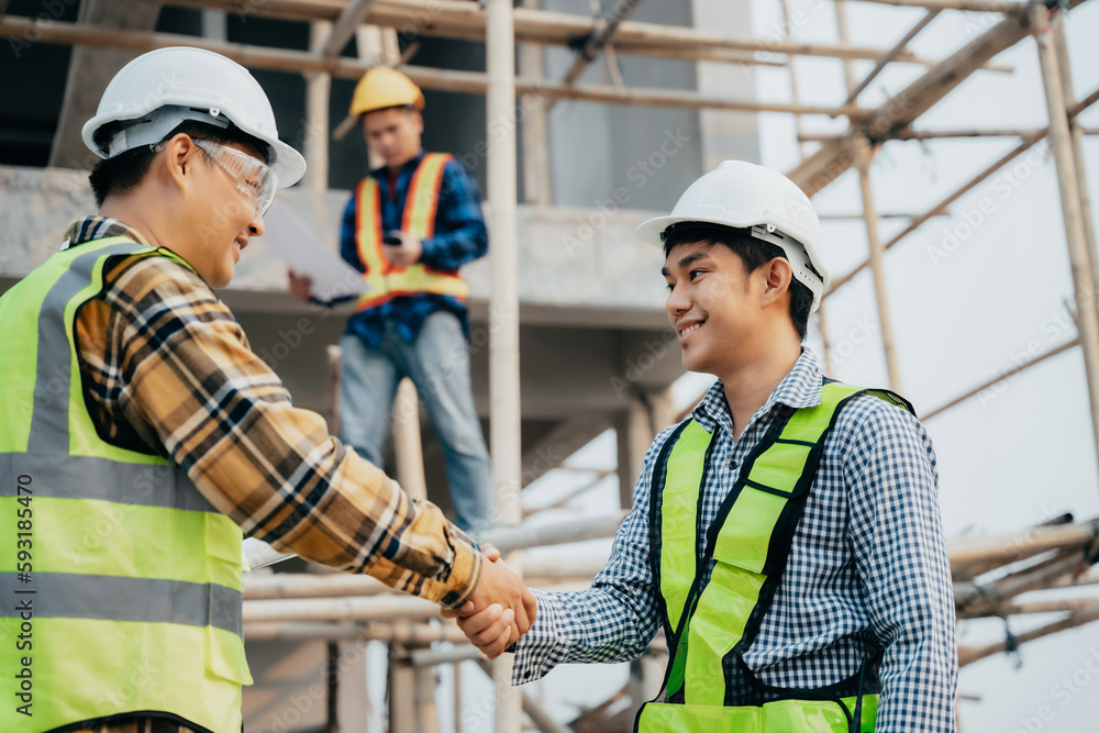 Construction workers, architects and engineers shake hands while ...