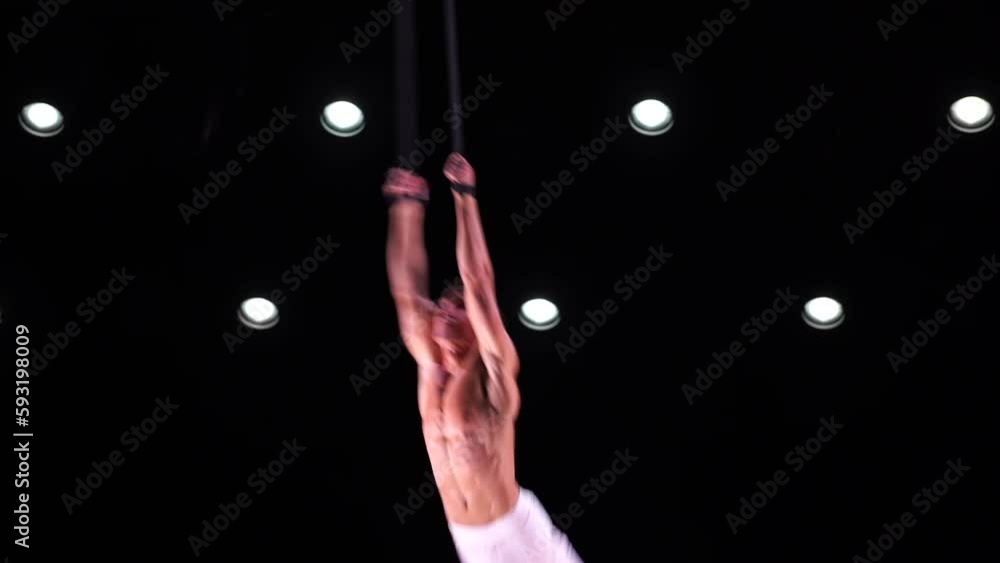 Male, muscular circus artist on Aerial straps on black stage background ...