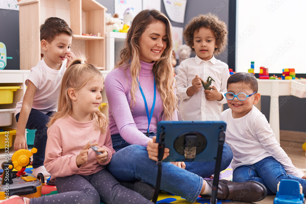 Woman and group of kids having lesson using touchpad at kindergarten ...