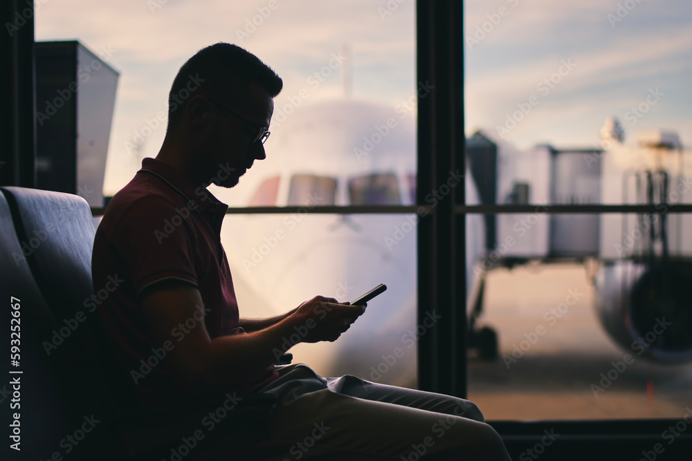 Traveler using phone while waiting for flight. Silhouette of man ...