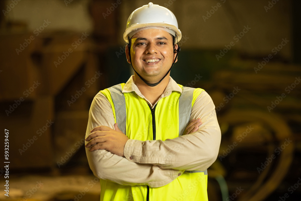 Portrait of happy Indian man engineer wearing safety hard hat and vest ...