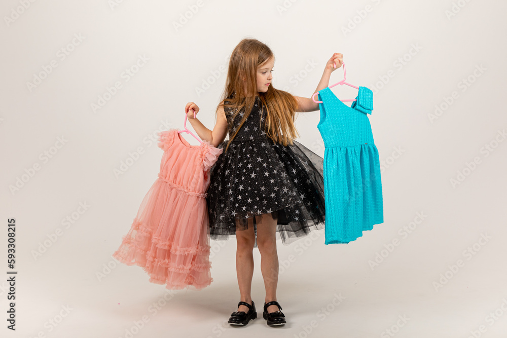 Little girl choosing dresses on white background. Child in black dress ...