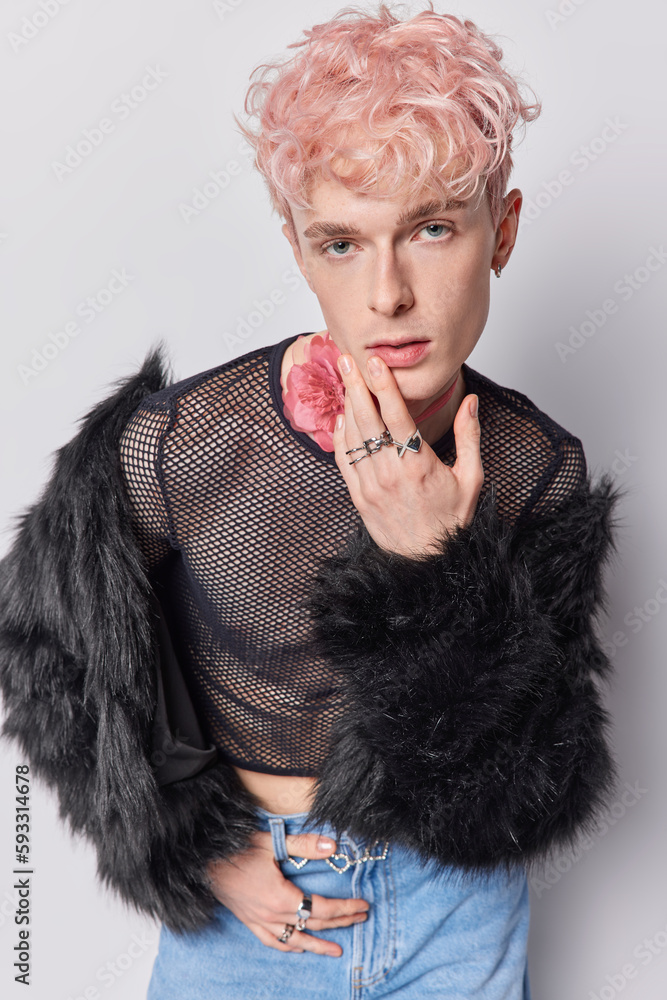 Young transgender man touches face looks seriously at camera wears net ...