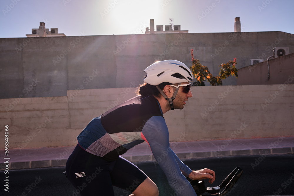 Fit male athlete on time trial aero bike in a relaxed position, riding ...