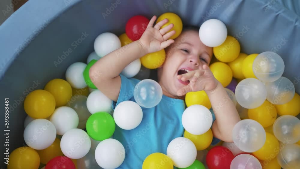 a child play in a dry pool with colored balls. happy family kid dream ...
