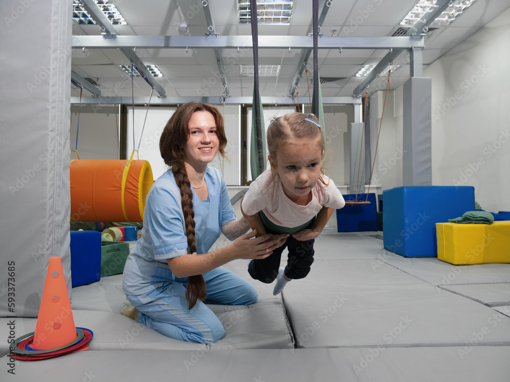 Child with physiotherapist on swing during sensory integration session ...