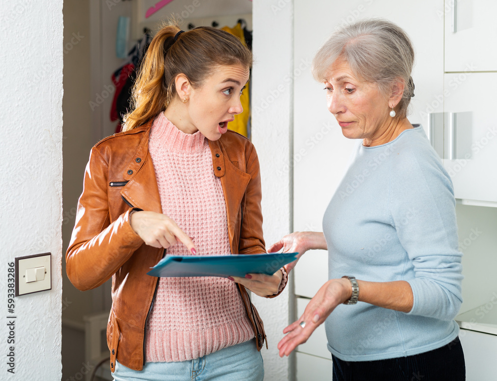 Angry young female householder demanding upset older woman to pay ...