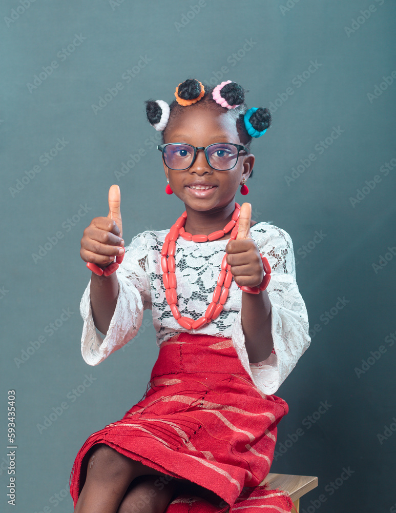 Studio portrait of a sitting African Nigerian female girl child with ...