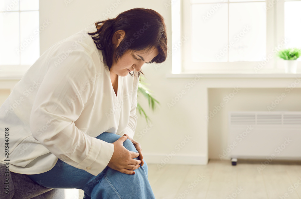 Foto de Portrait of young fat overweight woman holding a knee suffering ...