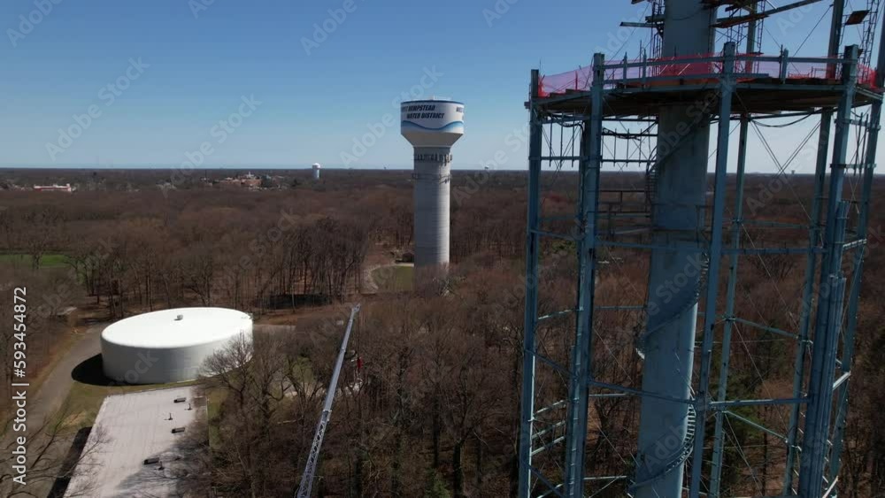 An aerial view of a water tower being dismantled on a sunny day on Long ...