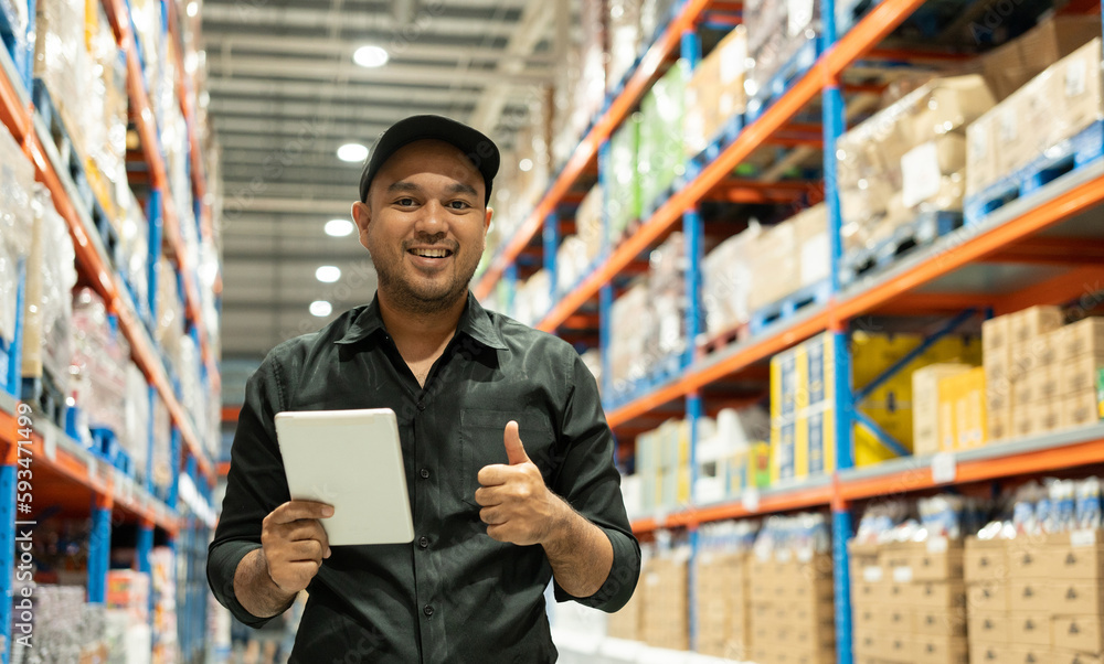 Warehouse worker wearing a hat and black shirt hands holding tablet ...