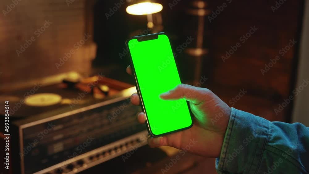 Shot of hands man using scrolling mobile phone with a vertical green ...
