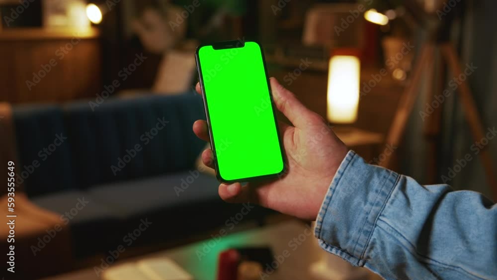 Hands using scrolling mobile phone with a vertical green screen. Social media. Smartphone. Mock ...