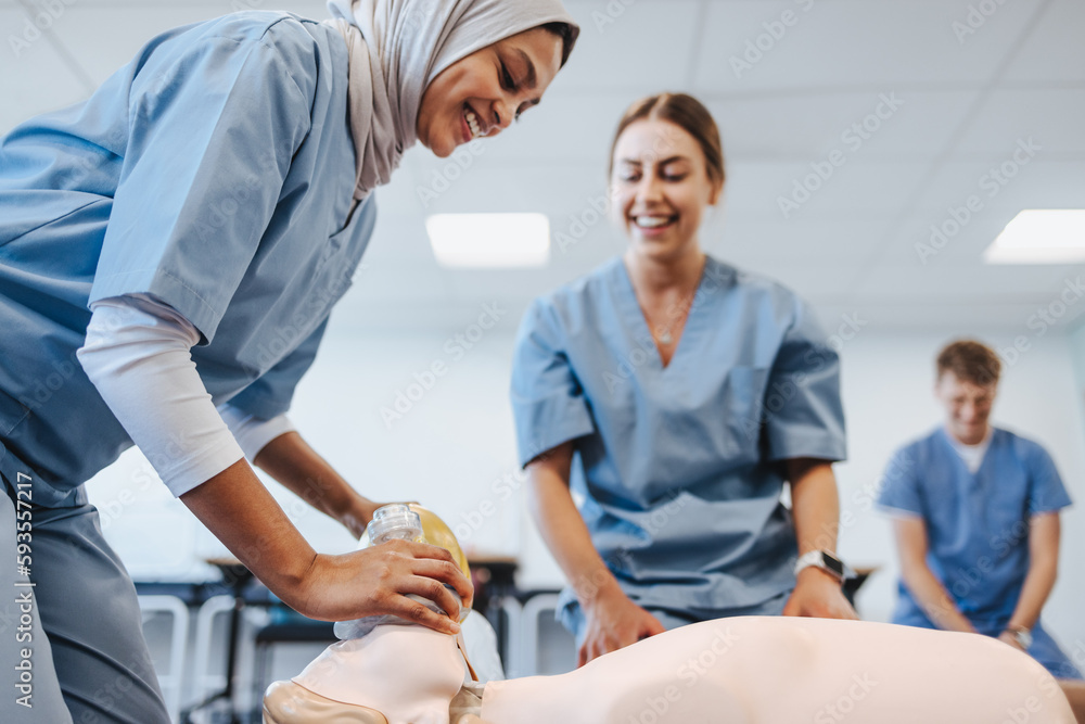 Diverse female medical students practicing CPR with an ambu bag and a ...