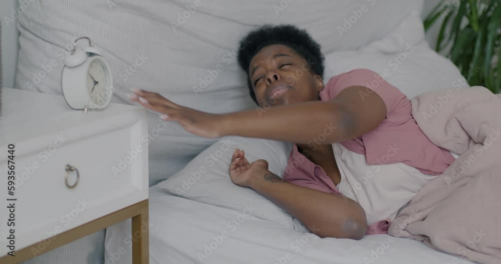 Portrait of sleepy African American woman in pajamas waking up turning ...