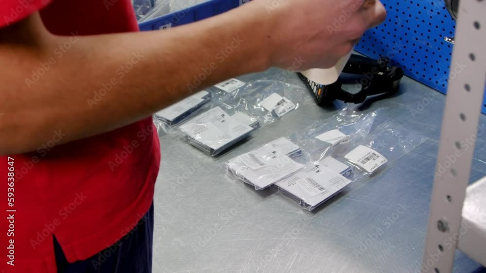 Male warehouse worker in work uniform removes stickers from paper and ...