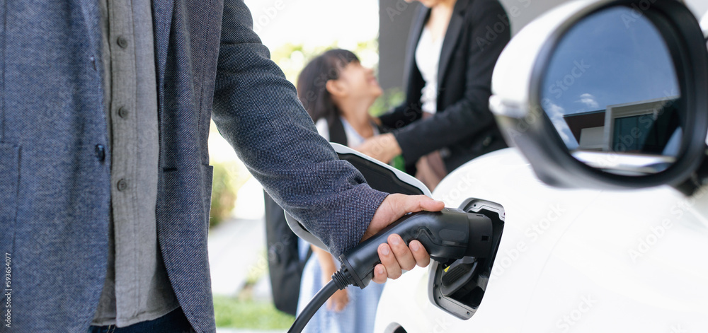 Closeup focus hand insert EV charger plug to electric vehicle at home ...