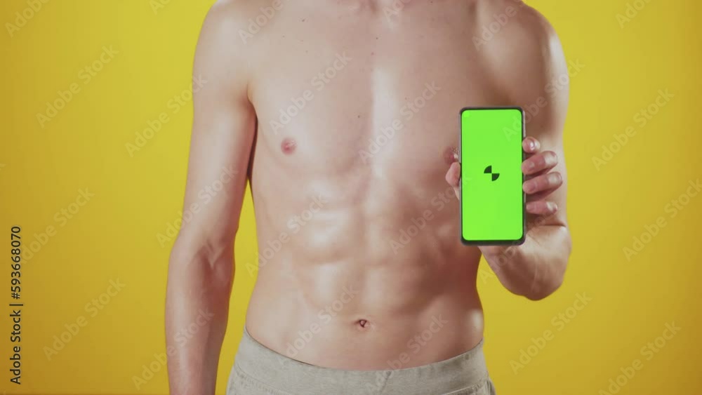 Male athlete holds phone with chromakey. Torso of an athletic man with ...