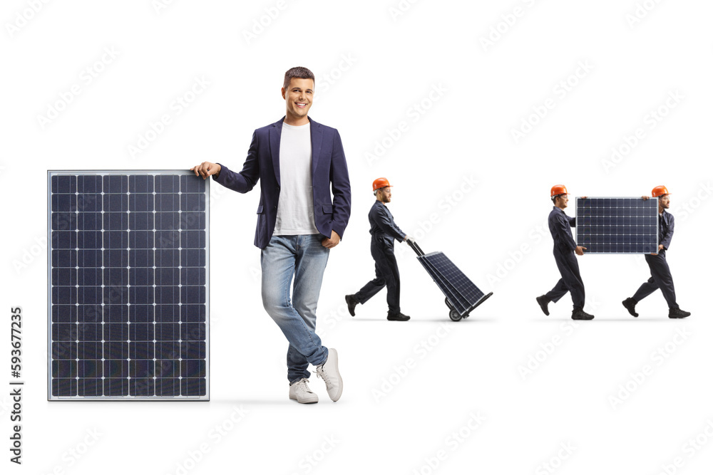 Man leaning on a solar panel and factory workers transporting panels ...