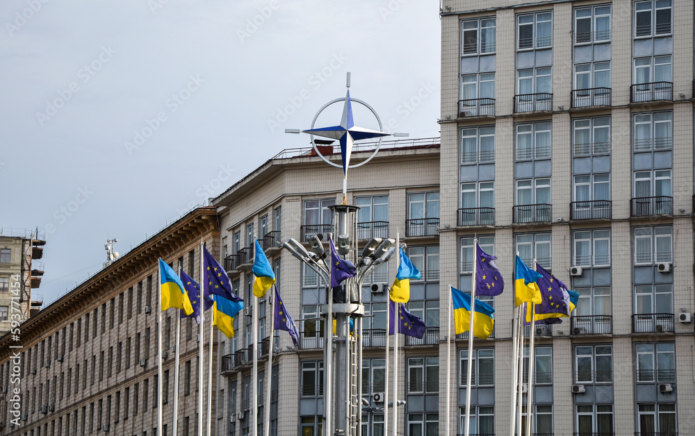 Flags of Ukraine and the European Union waving together under emblem of ...