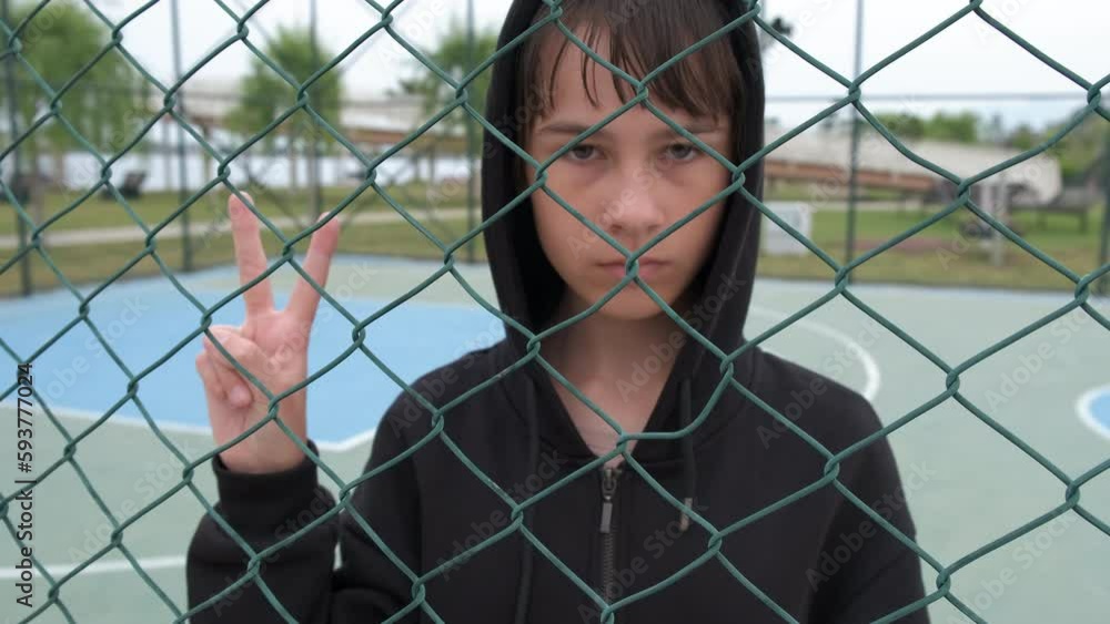 Bullying problems by metal fence. A view of upset teen girl stay by ...