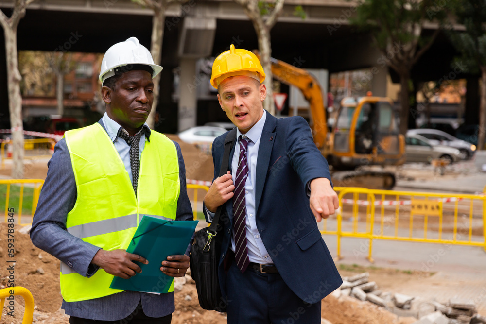 Young confident foreman, controlling the course of laying paving slabs ...