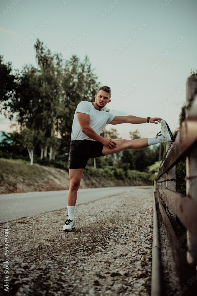 Athlete performing leg stretching exercises after a run in a natural ...