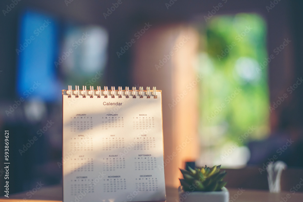 Desktop calendar, clock, and cactus placed on student wooden desk ...