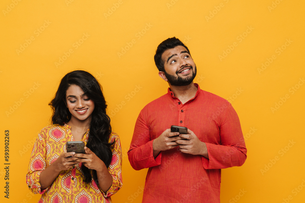 Indian man and woman using mobile phones while standing isolated over ...