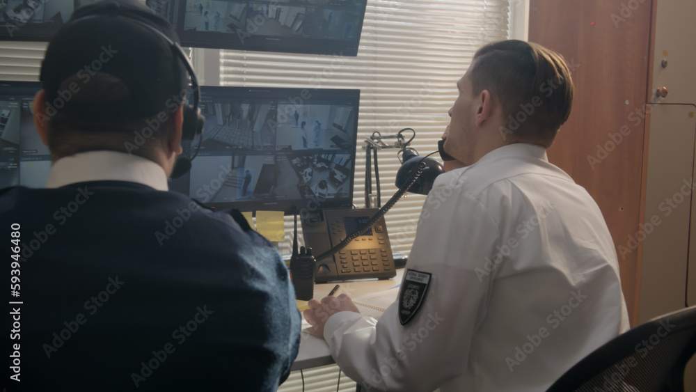 Security officer in headset monitors cameras on computer. Operator uses ...