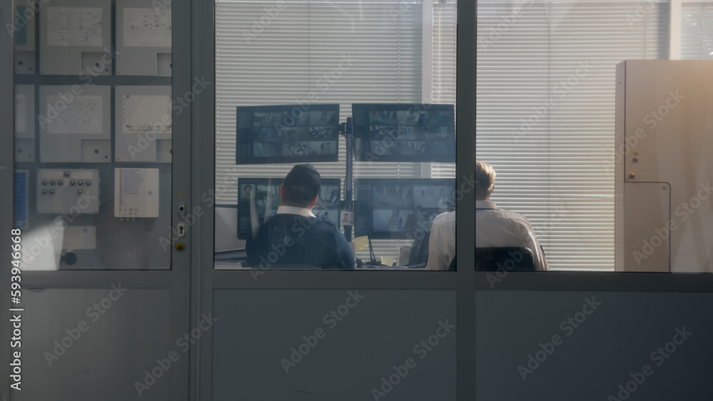 Security operator in uniform comes in observation room, sits at the ...