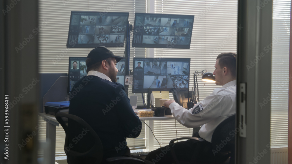 Two security guards talk, have lunch while control CCTV cameras on ...